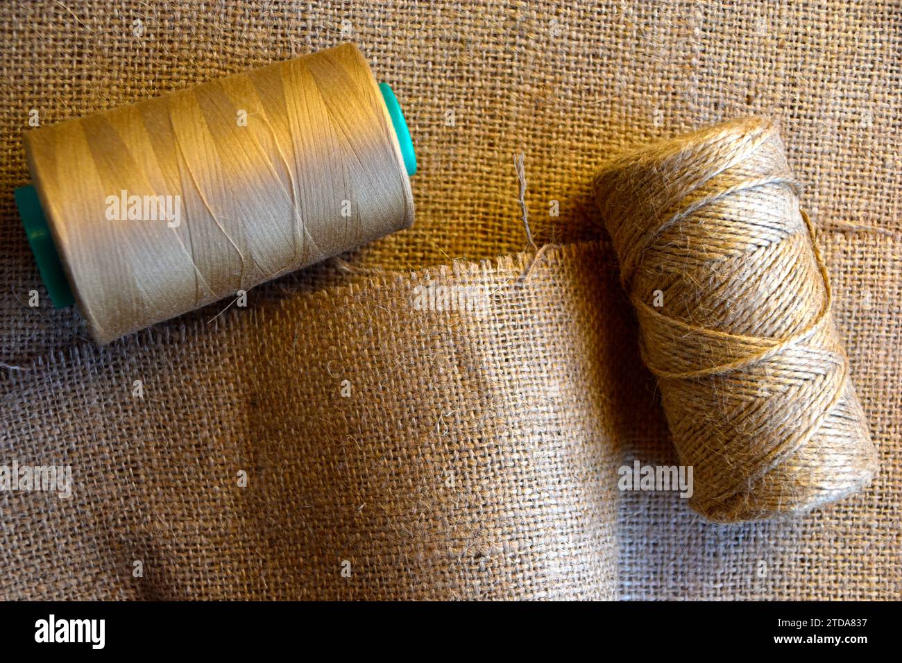 Skeins of thread on crumpled burlap. Yellow threads on coarse cloth ...