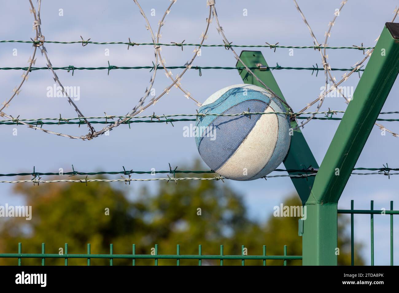Old , abandoned basketball trapped in barb wire at the border, blurry ...
