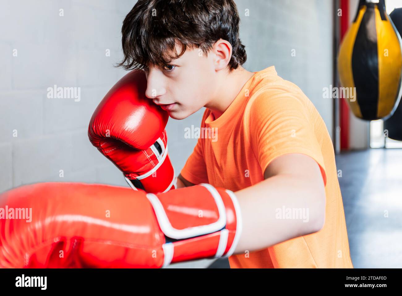 Horizontal photo caucasian teen boy with orange t-shirt and red boxing ...