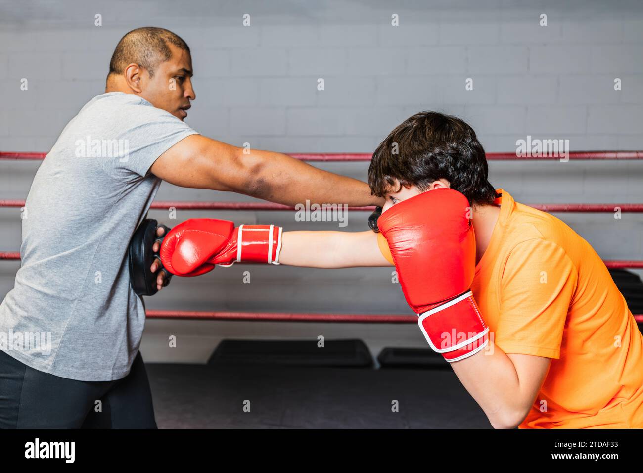 Horizontal photo caucasian teen boy with red boxing gloves and orange t ...