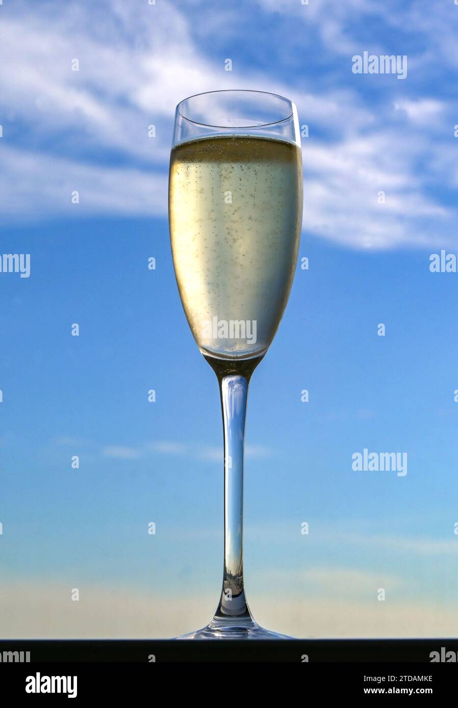 Flute glass of chilled champagne on the window sill of an airport ...