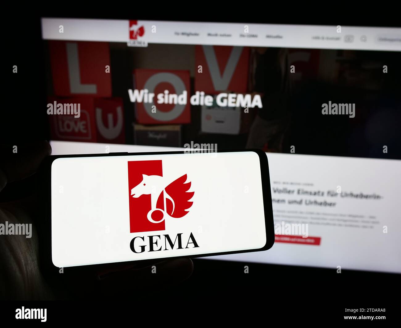 Person holding smartphone with logo of German collecting society GEMA ...