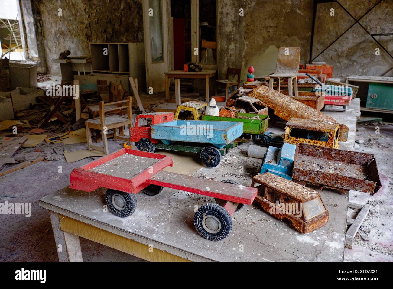 A room with old, rusty toy trucks on a table, surrounded by debris and ...