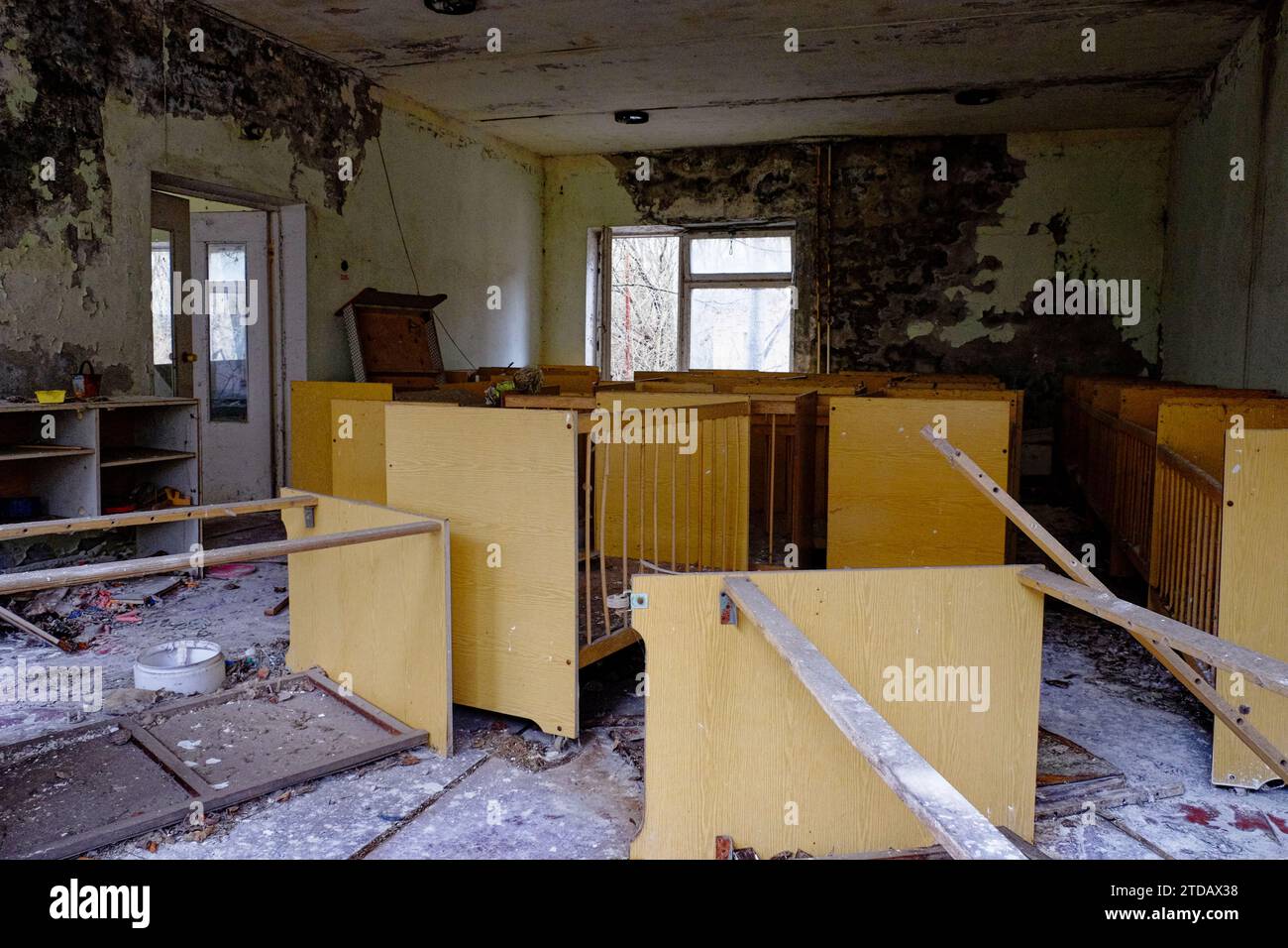 The image shows a dilapidated room with crumbling walls, debris on the floor, and disassembled ...