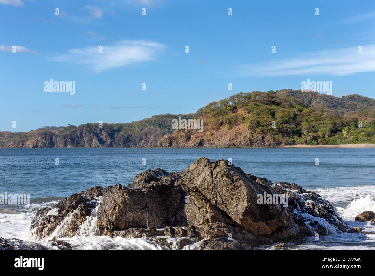 Nature landscape showing white surf at the base of a foreground rock in ...
