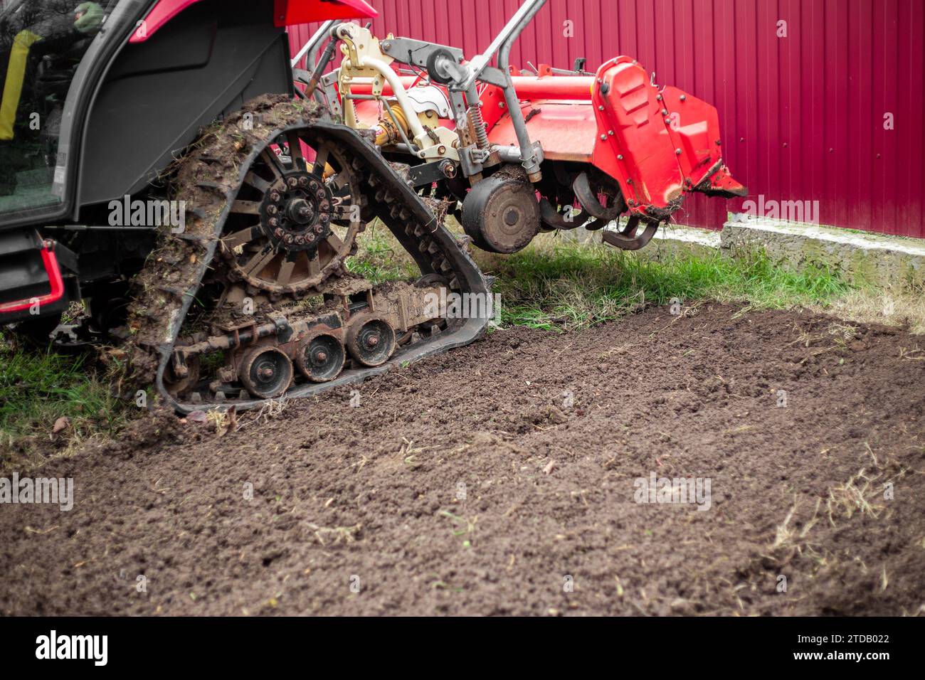 A mini tractor with a milling machine plows the ground on an ...