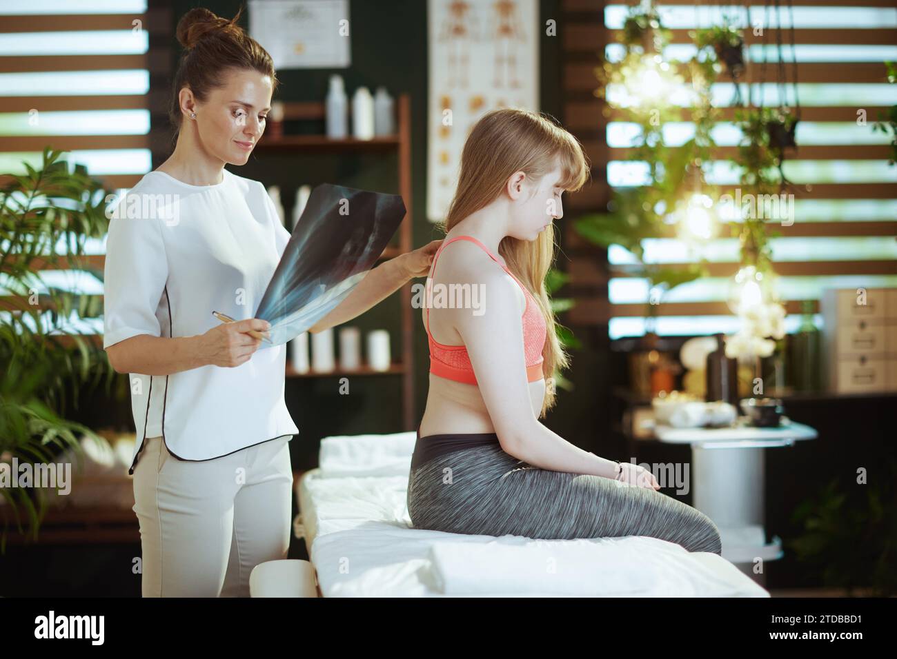 Healthcare time. concerned female massage therapist in massage cabinet with x-ray and teenage ...