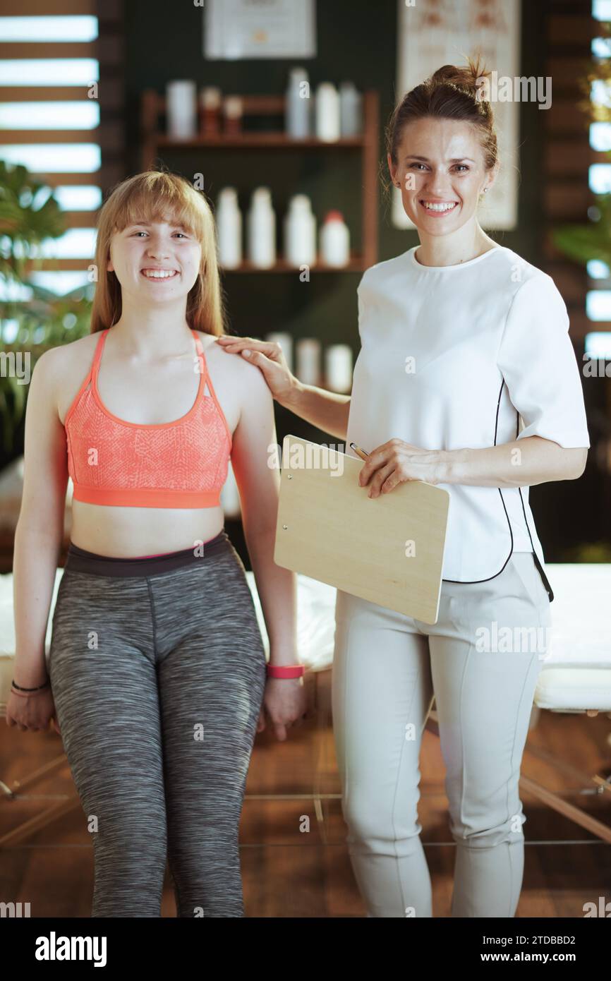 Healthcare time. happy female medical massage therapist in massage cabinet with clipboard and ...
