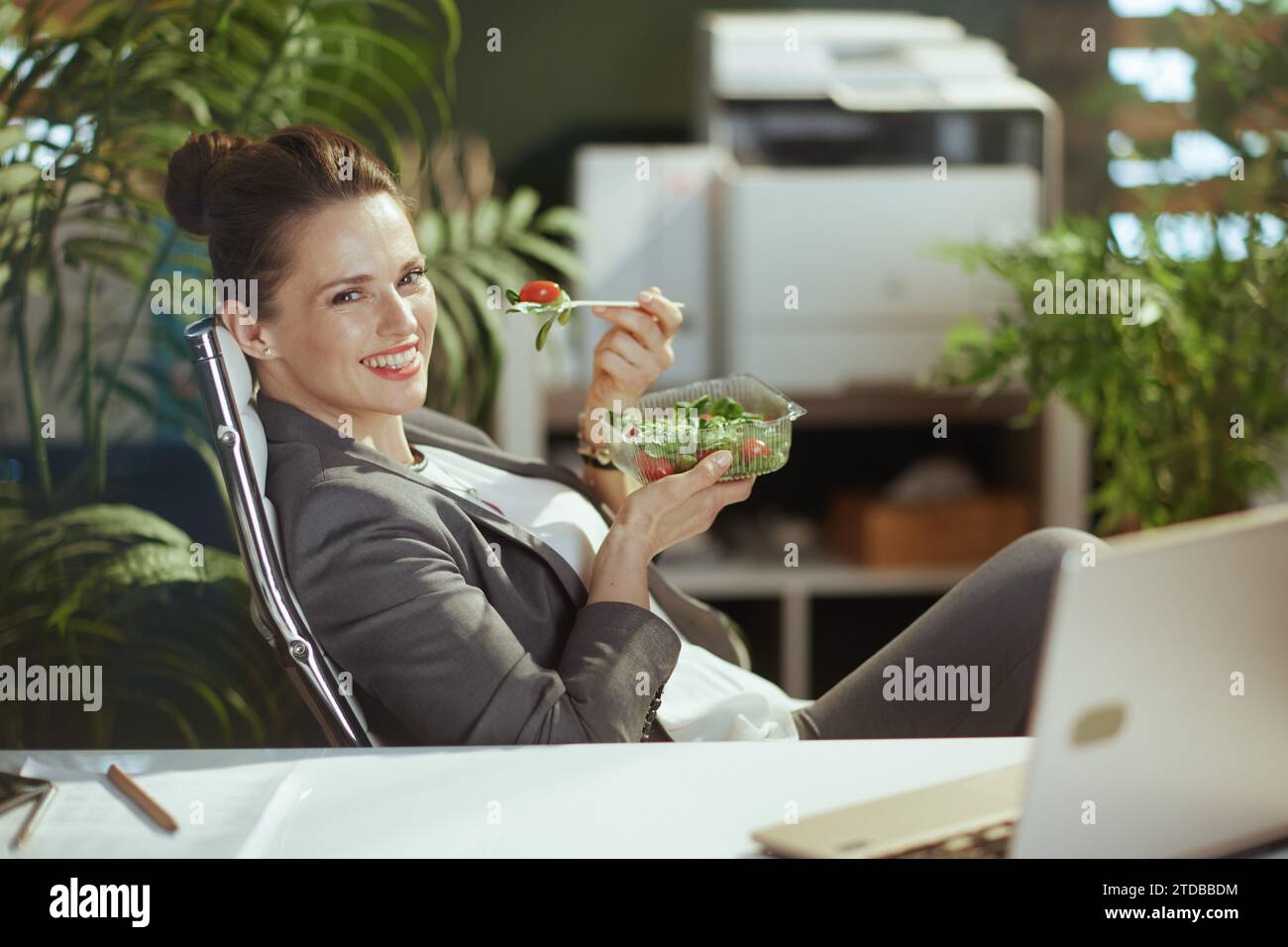 Sustainable workplace. happy modern 40 years old woman worker in a grey ...