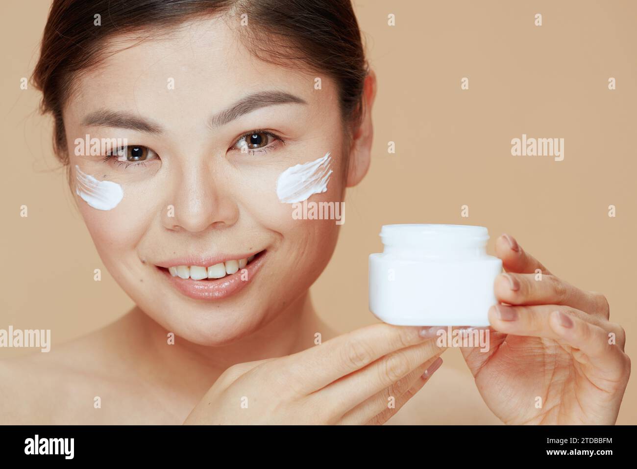 Portrait of modern asian woman with facial cream jar and facial cream ...