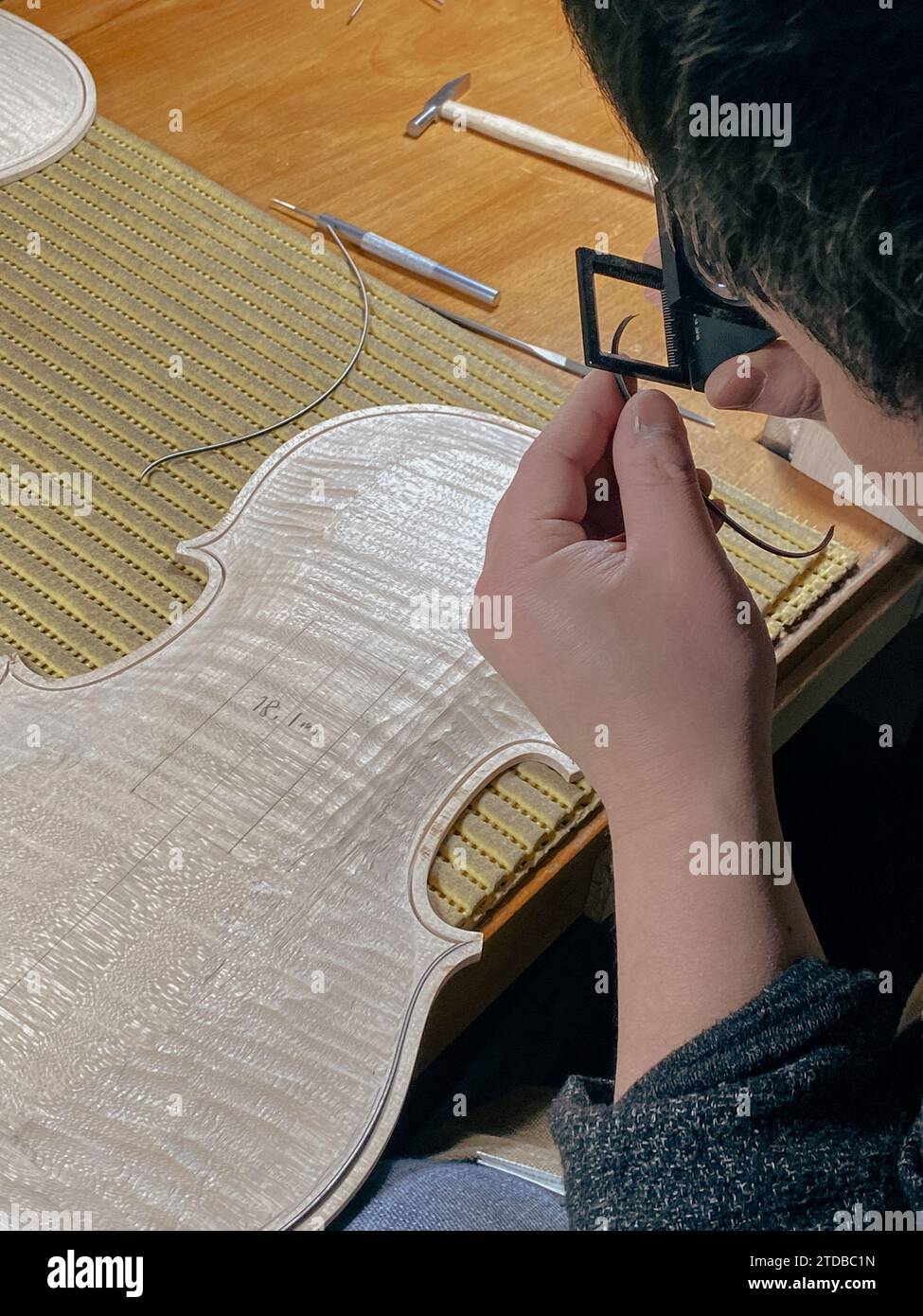 violinmaker performing purfling to new raw violin top plate using loupe ...