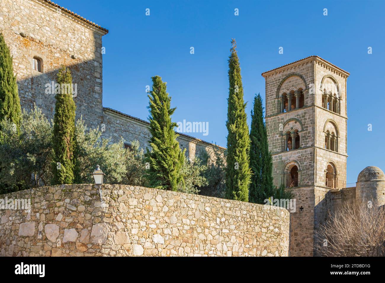 Tower, trees and a tall flat roofed tower made of honey coloured stone ...