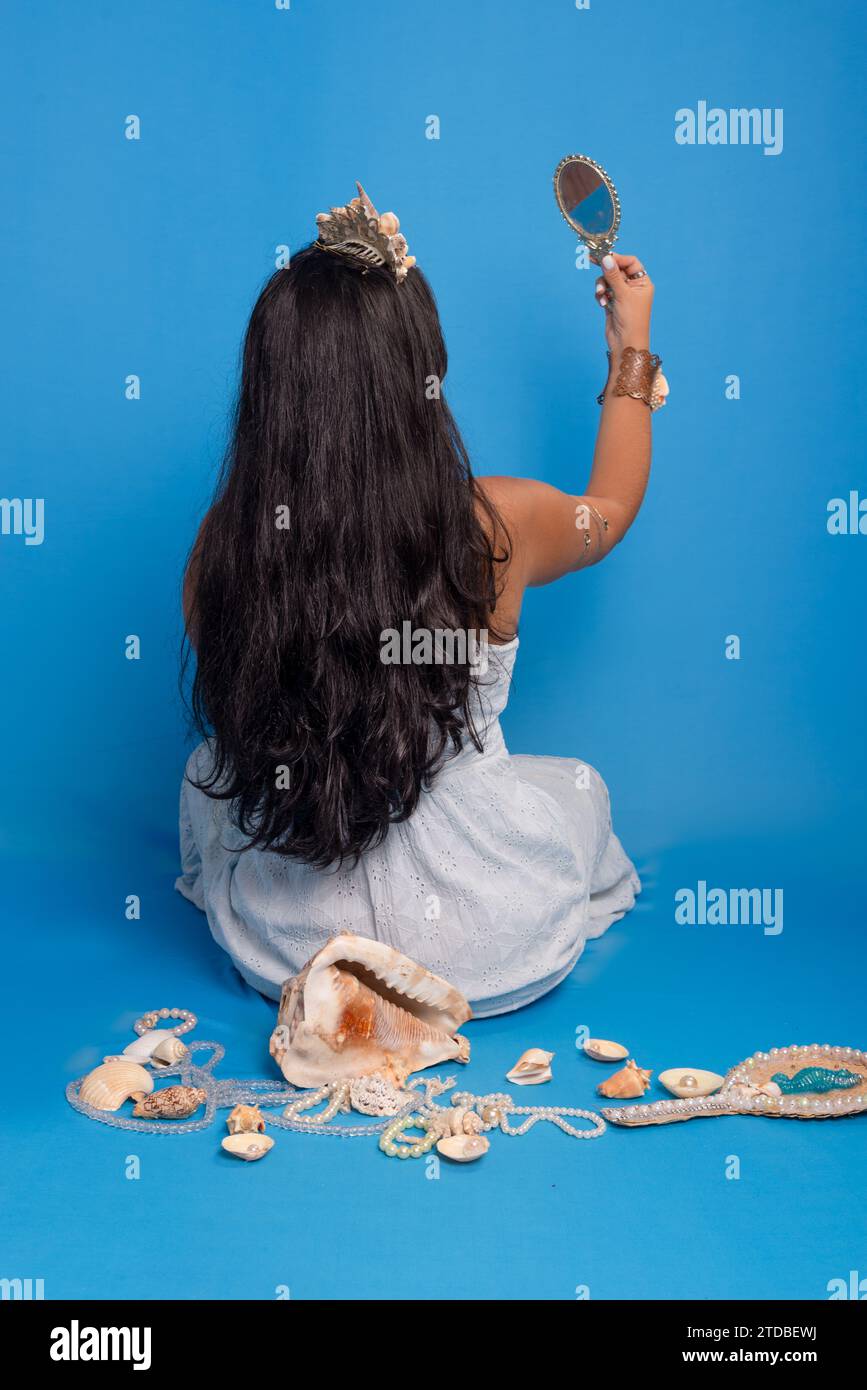 Beautiful black-haired woman wearing white clothing, sitting against ...