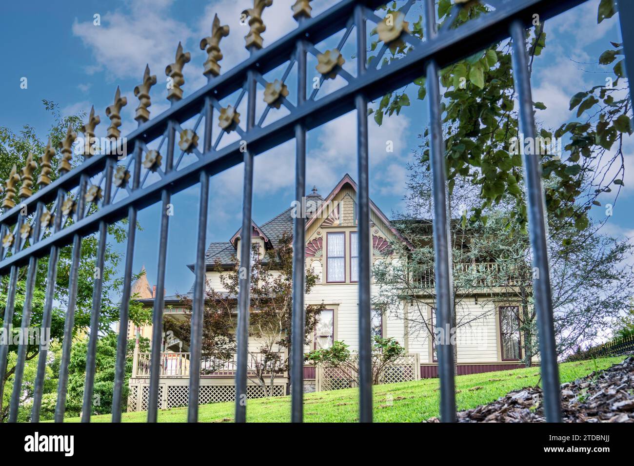 Looking through its wrought iron fence at an ornate Victorian mansion ...