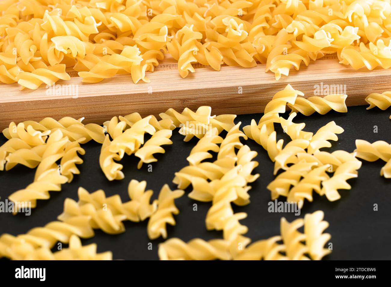 Uncooked Fusilli Pasta Scattered on Wooden Board and Black Table. Raw ...