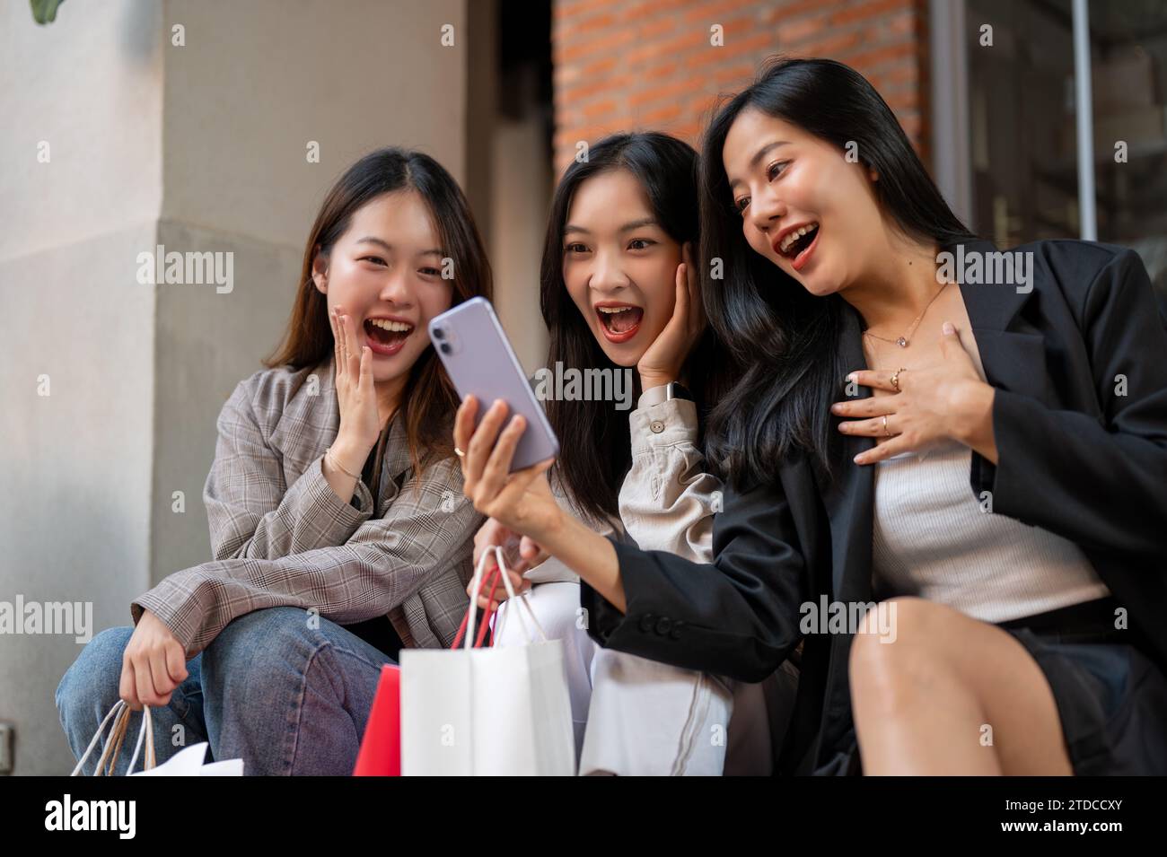 A group of excited and amazed Asian female friends are looking at a ...