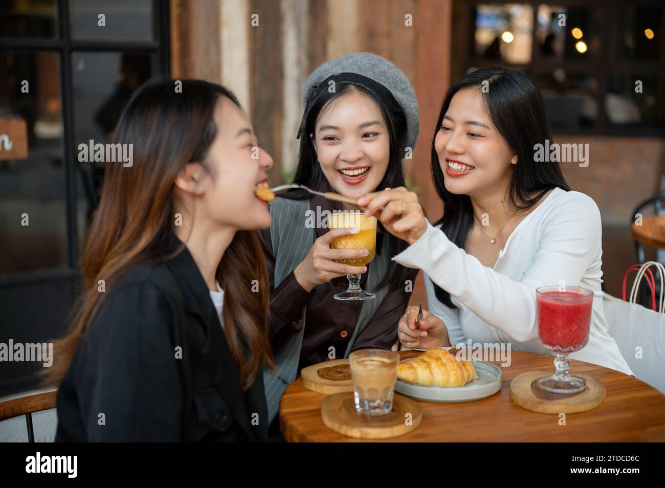 Group of cheerful and pretty Asian female friends are enjoying eating ...