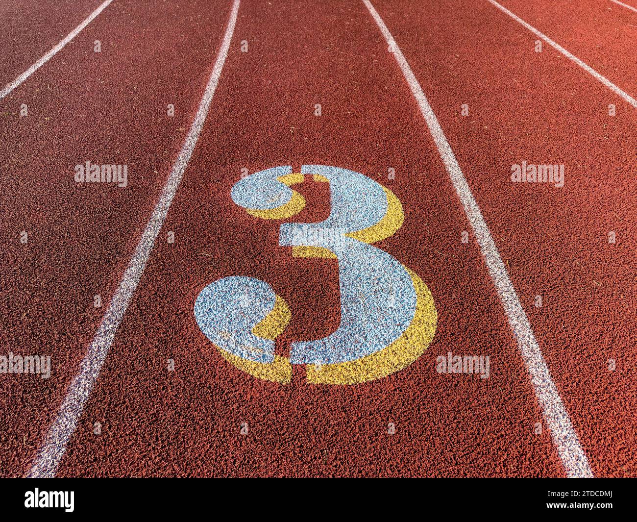 Close up lane number 3 on a new red running track with white lane lines ...