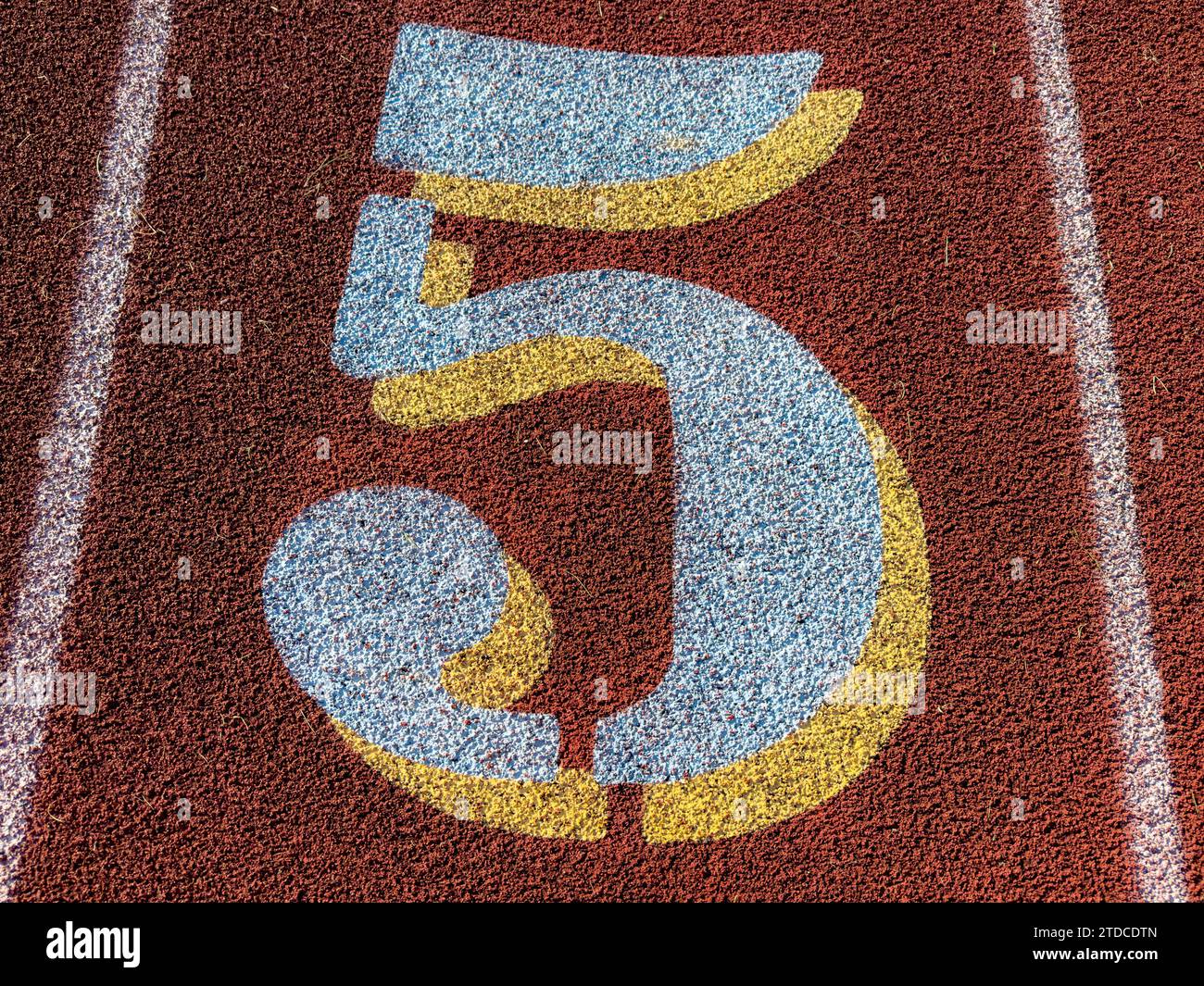 Close up lane number 5 on a new red running track with white lane lines ...