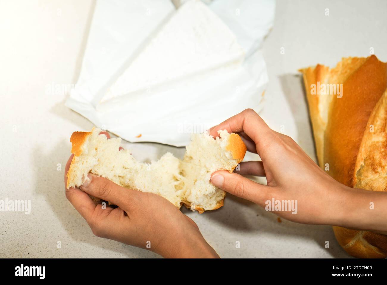 Woman hands breaking freshly baked loaf of bread to make cheese ...