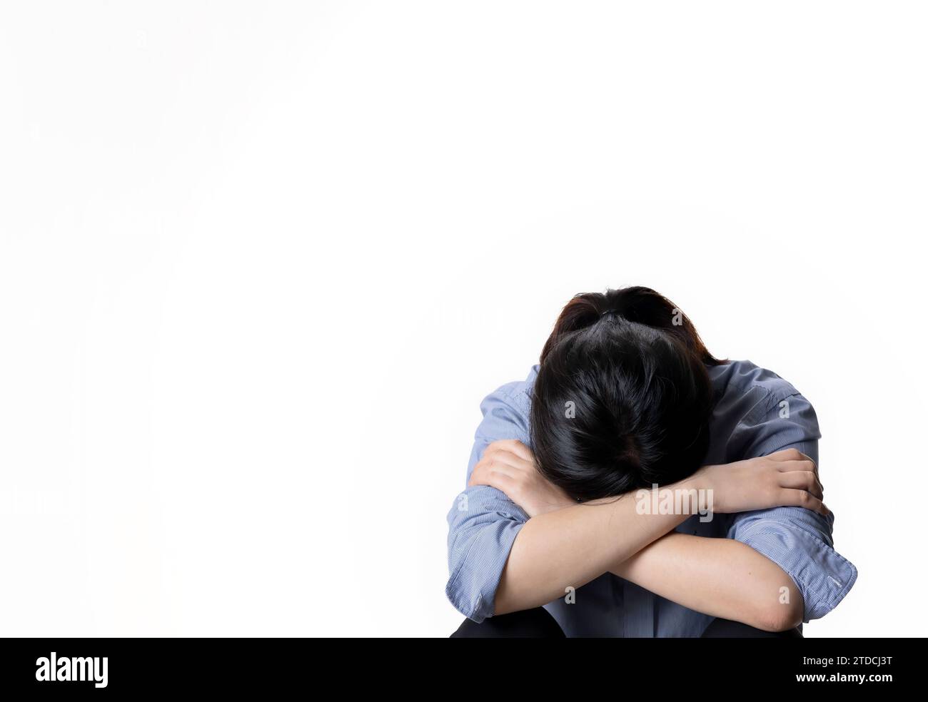 A woman in despair with her head down in front of a white background ...