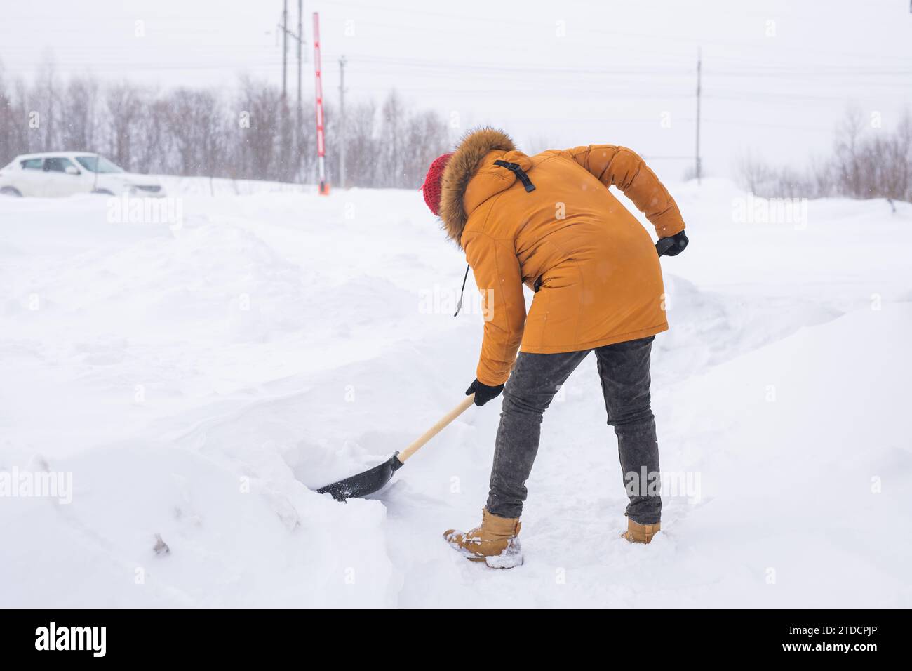 Young man clearing snow in his backyard village house with shovel ...