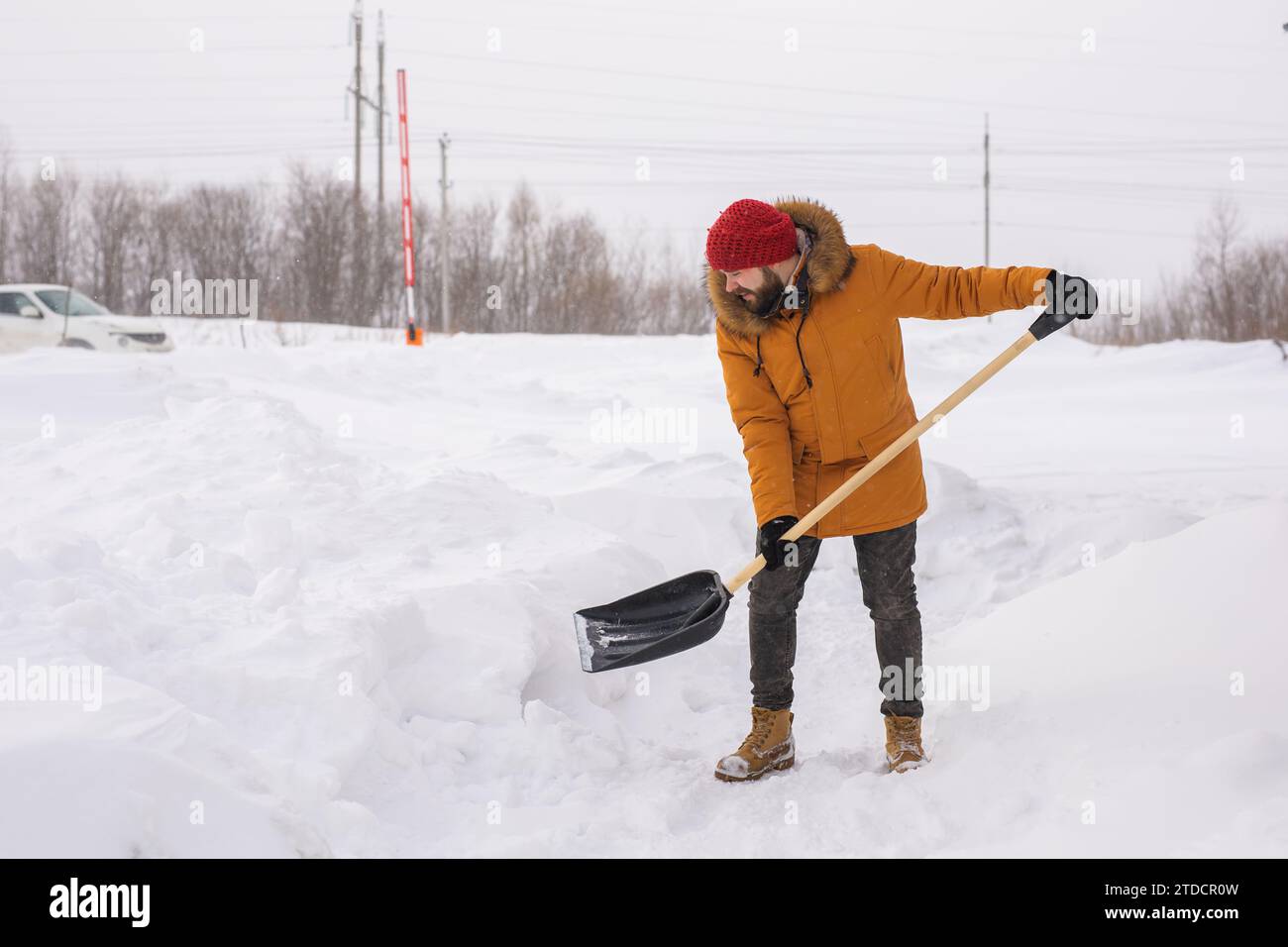 Young man clearing snow in his backyard village house with shovel ...