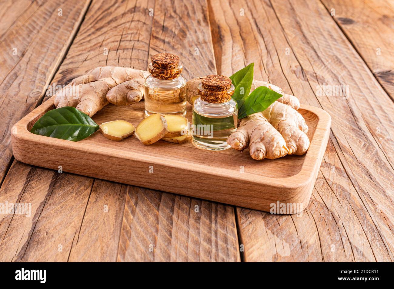 Natural ginger root oil in two glass bottles with cork cap on wooden ...