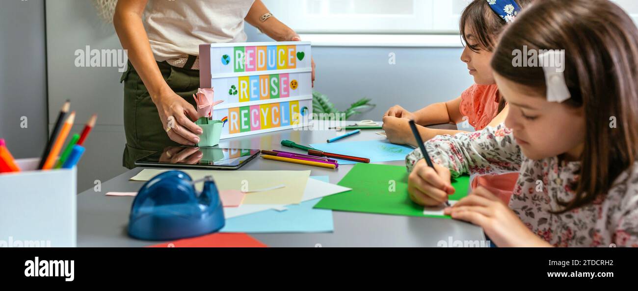Teacher holding lightbox with text reduce, reuse, recycle while ...
