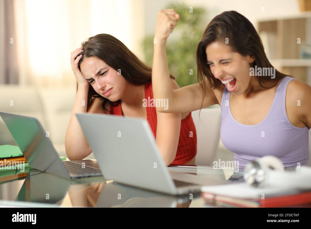 Happy student celebrating grades checking laptop beside a sad one at ...