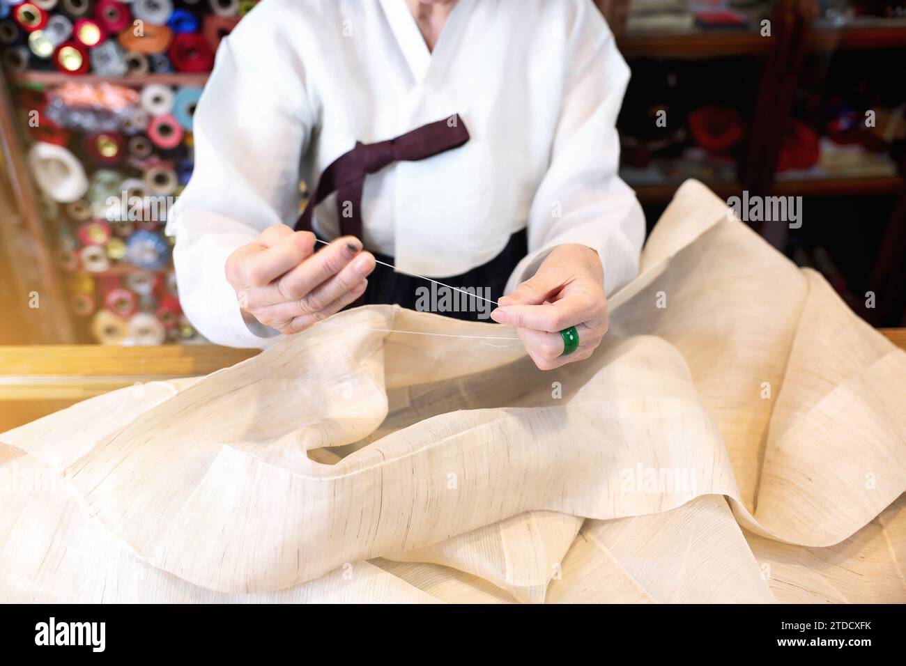 A master of traditional Korean clothing, a Hanbok expert, is sewing for ...
