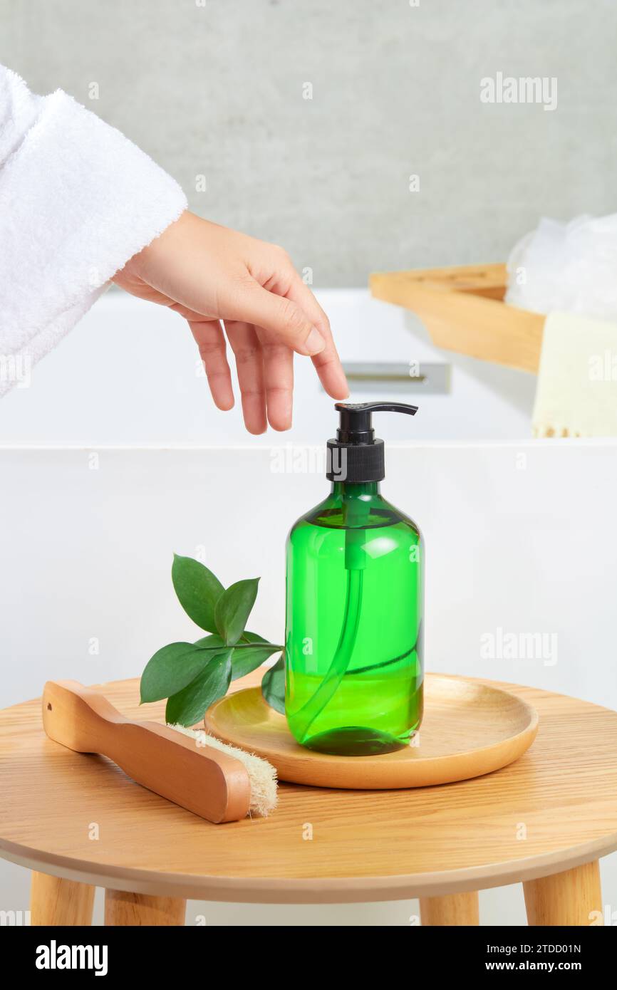 Front view of a hand above an unlabeled shampoo bottle with spray head ...