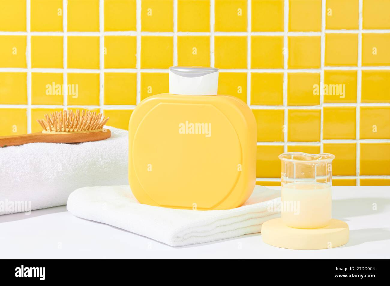 A blank yellow shower gel bottle rests on a white table against a ...