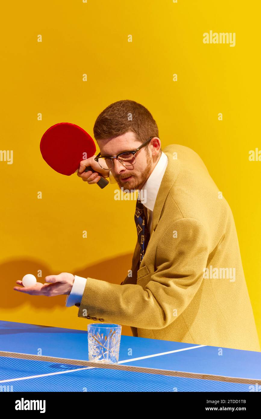 Concentrated young man in glasses, elegant suit playing table tennis ...