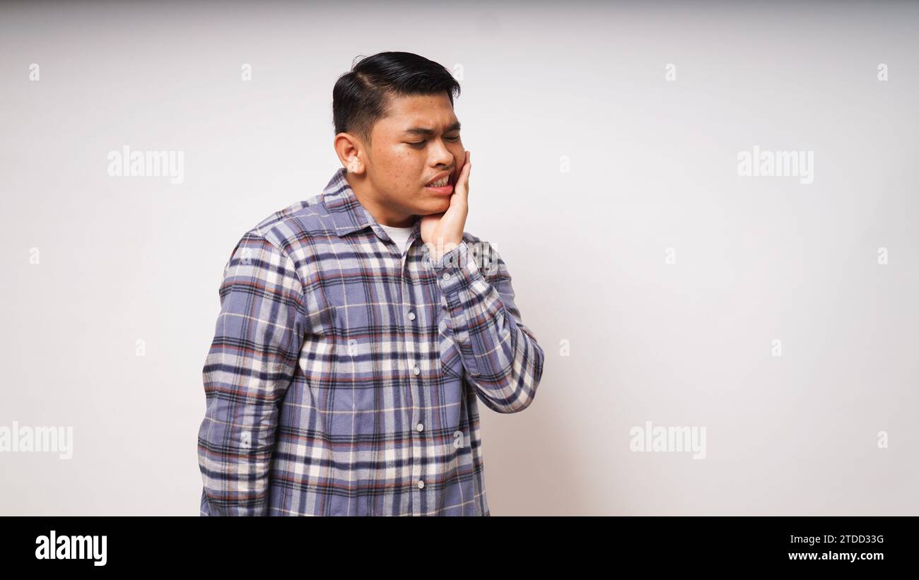 Toothache concept. Asian man touching his jaw with pain expression on ...