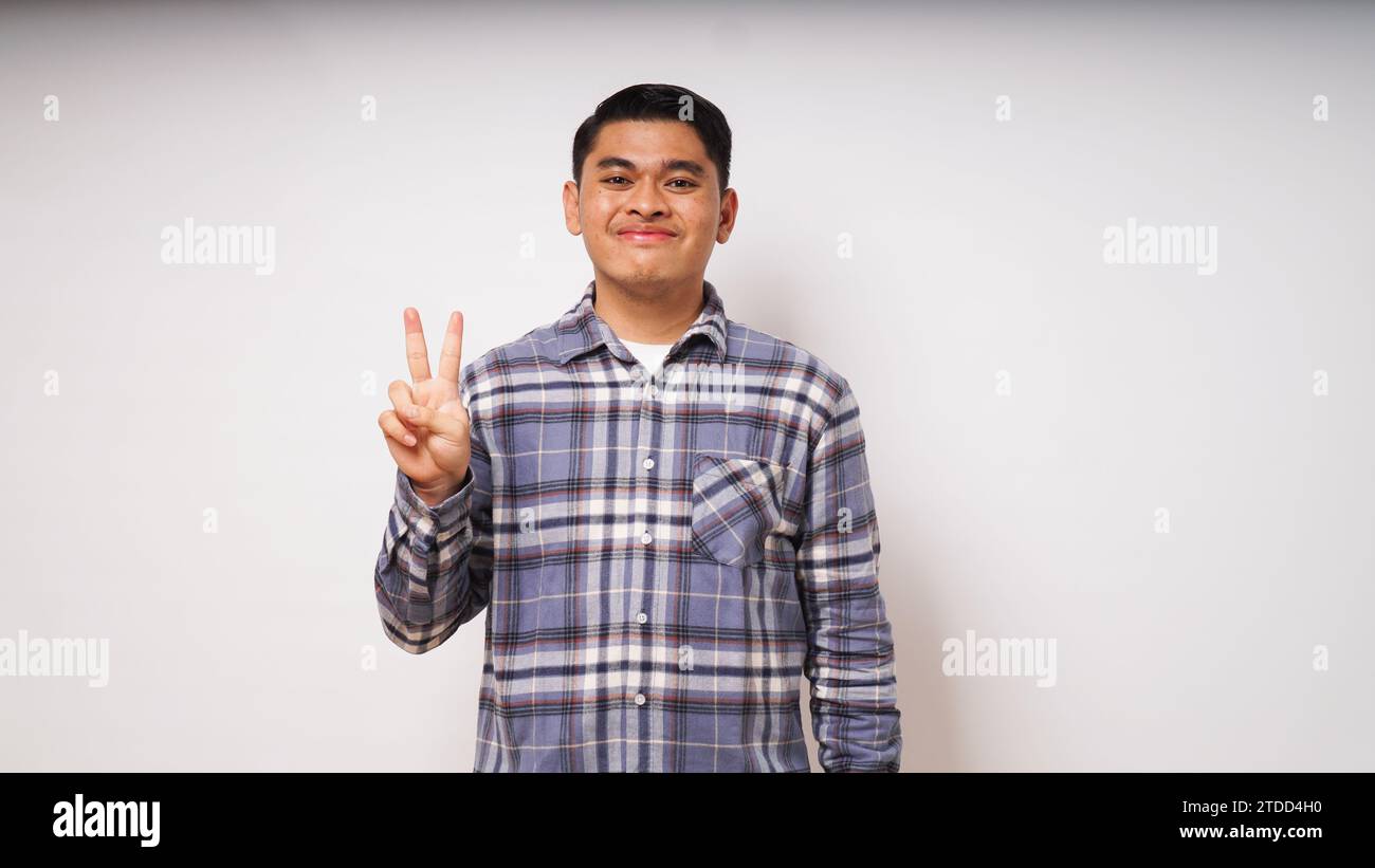 Young Asian man showing happy face expression while giving two fingers ...