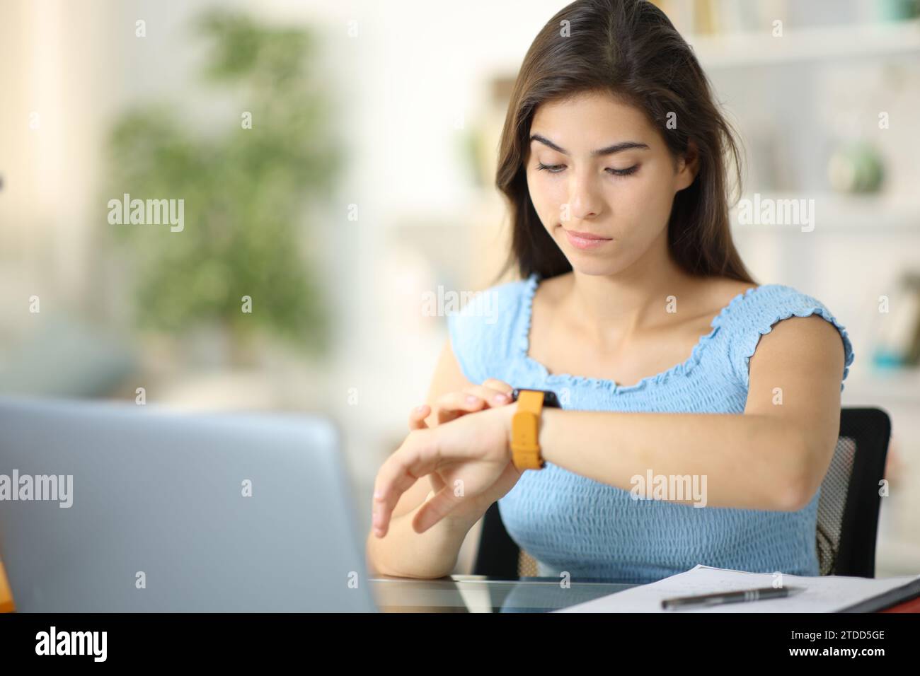 Suspicious woman checking smartwatch content sitting at home Stock ...