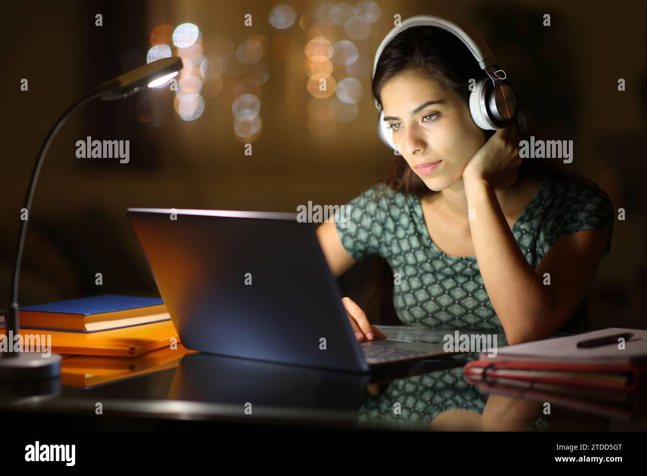 Student wearing headphone in the night studying watching tutorial on ...