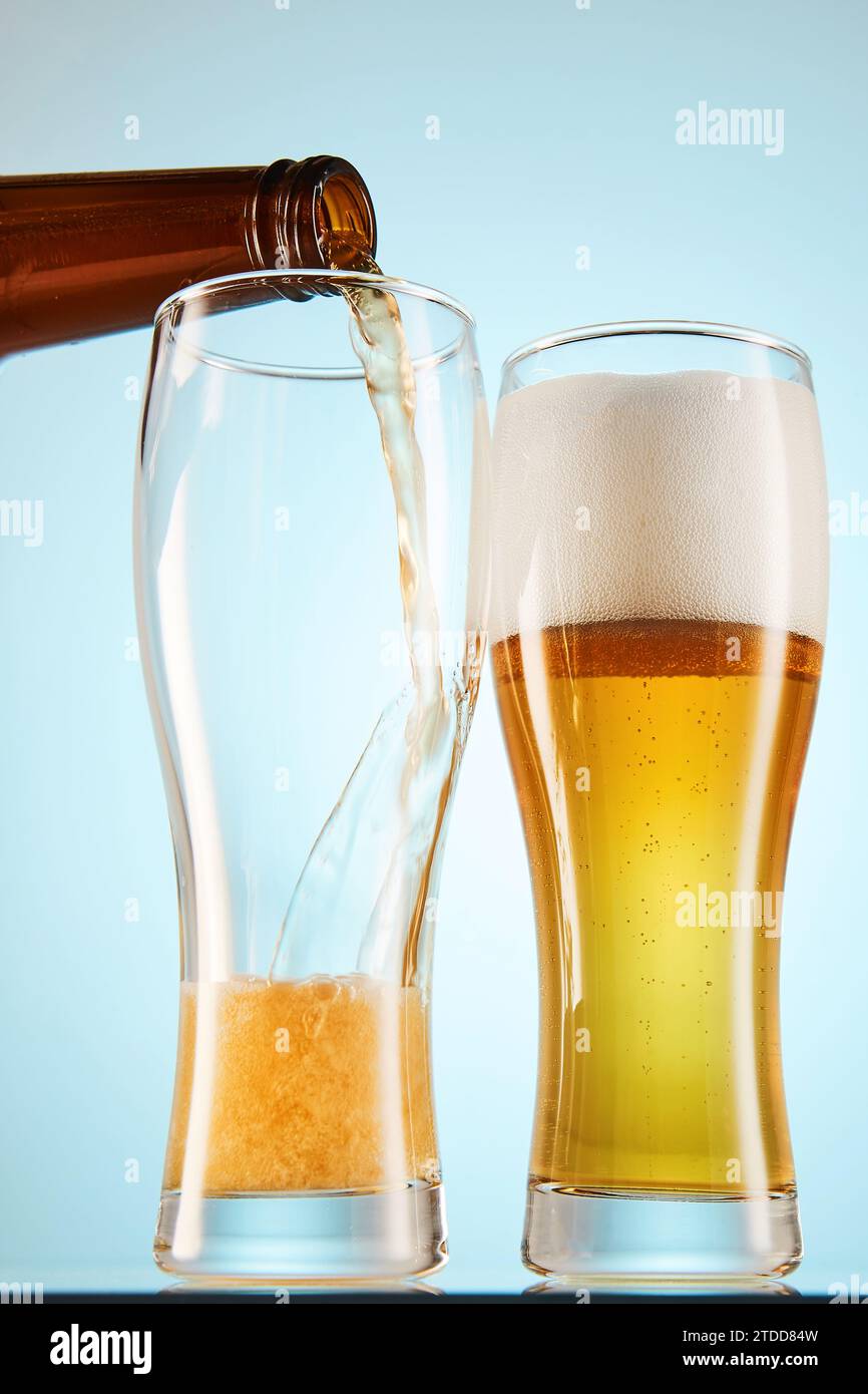 Lager, ale flows to empty tall glasses from bottle Stock Photo - Alamy