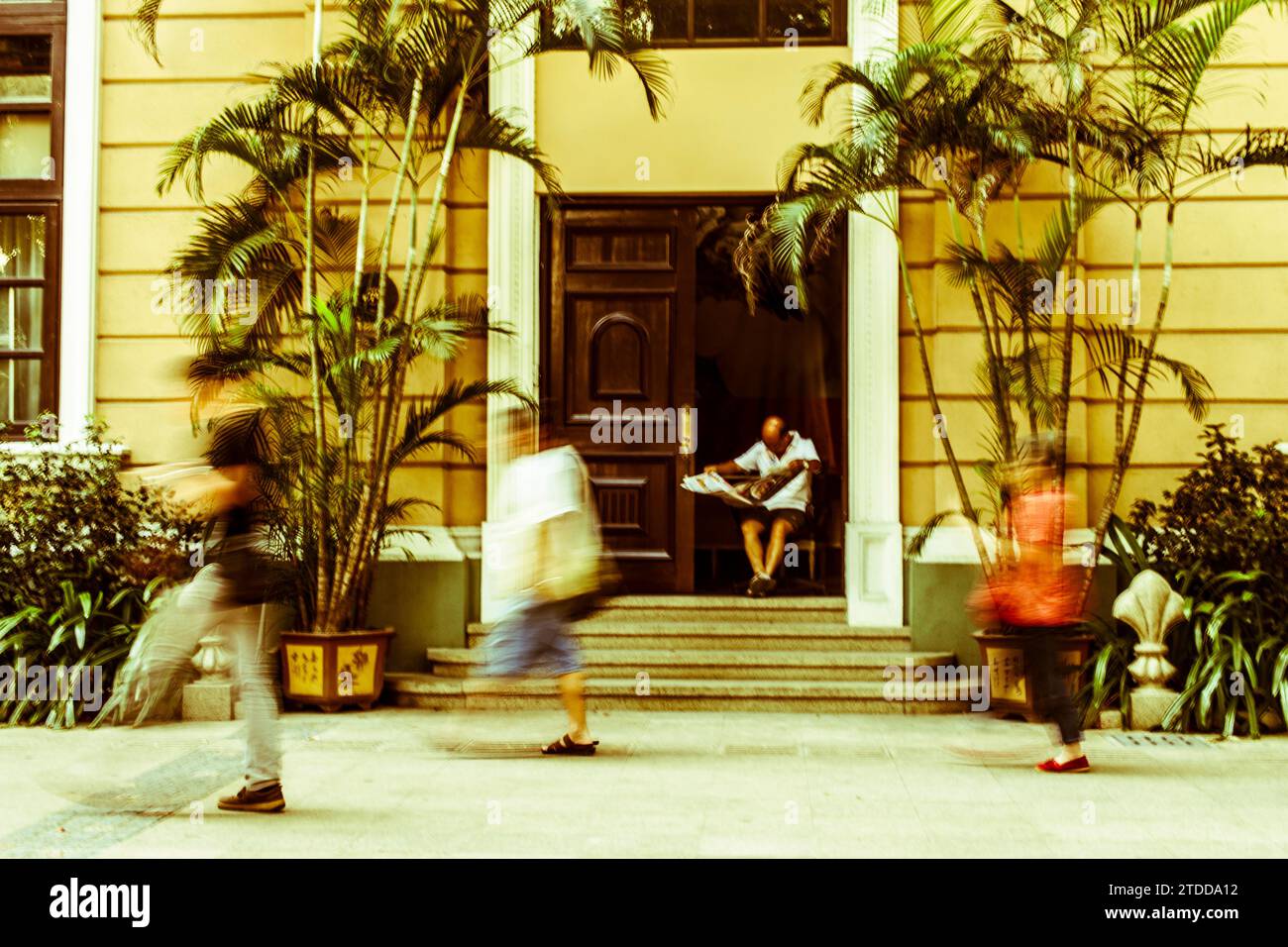 Chinese man reading a newspaper on a doorstep Stock Photo - Alamy