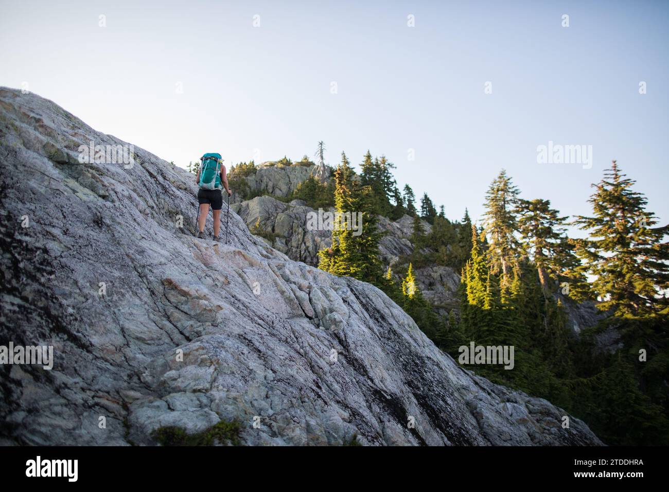 Rear view of backpacker hiking on a granite talus slope, Mt. Seymour ...