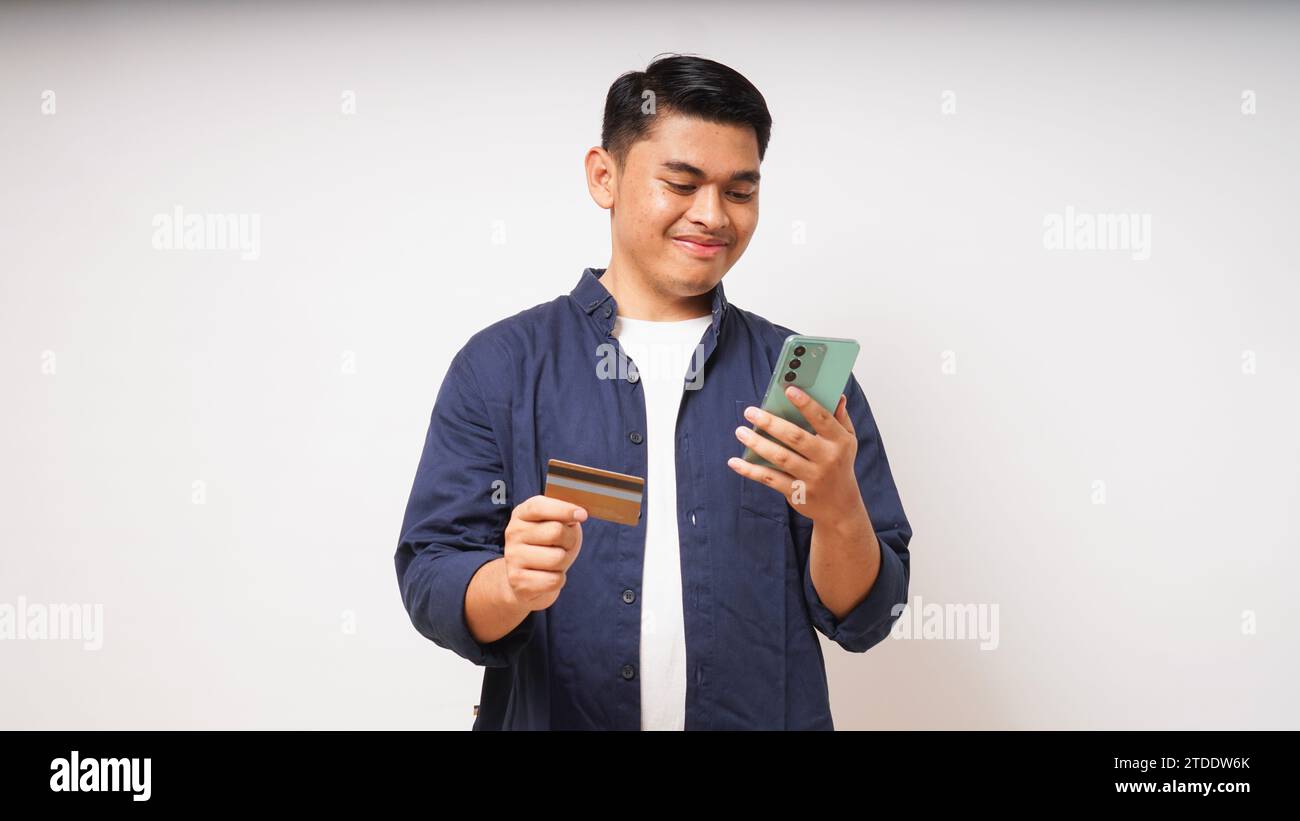 Portrait of satisfied happy Asian young man holding smart phone and ...