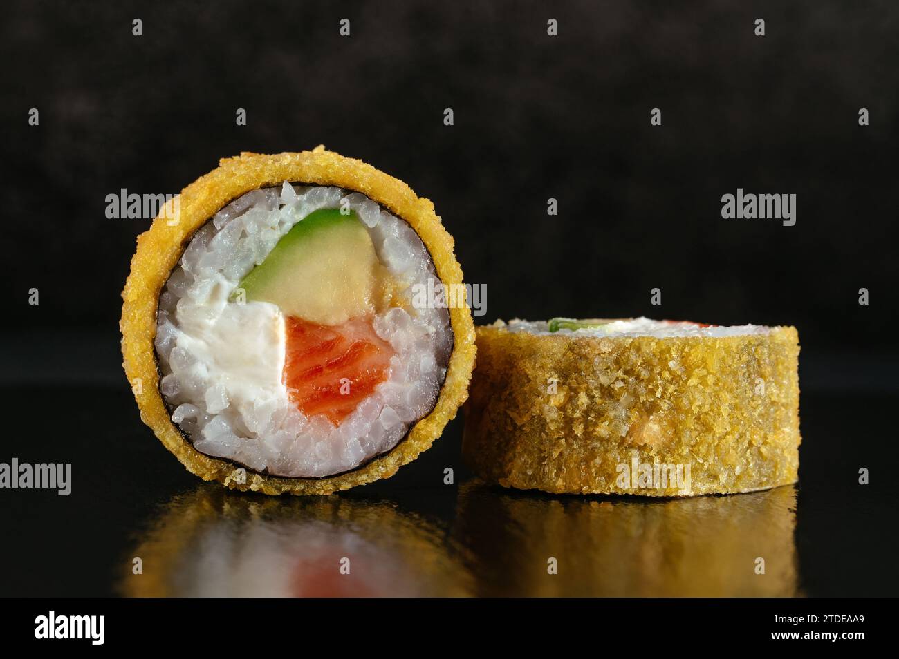 Deep-fried Japanese sushi rolls on a dark background with reflec Stock ...