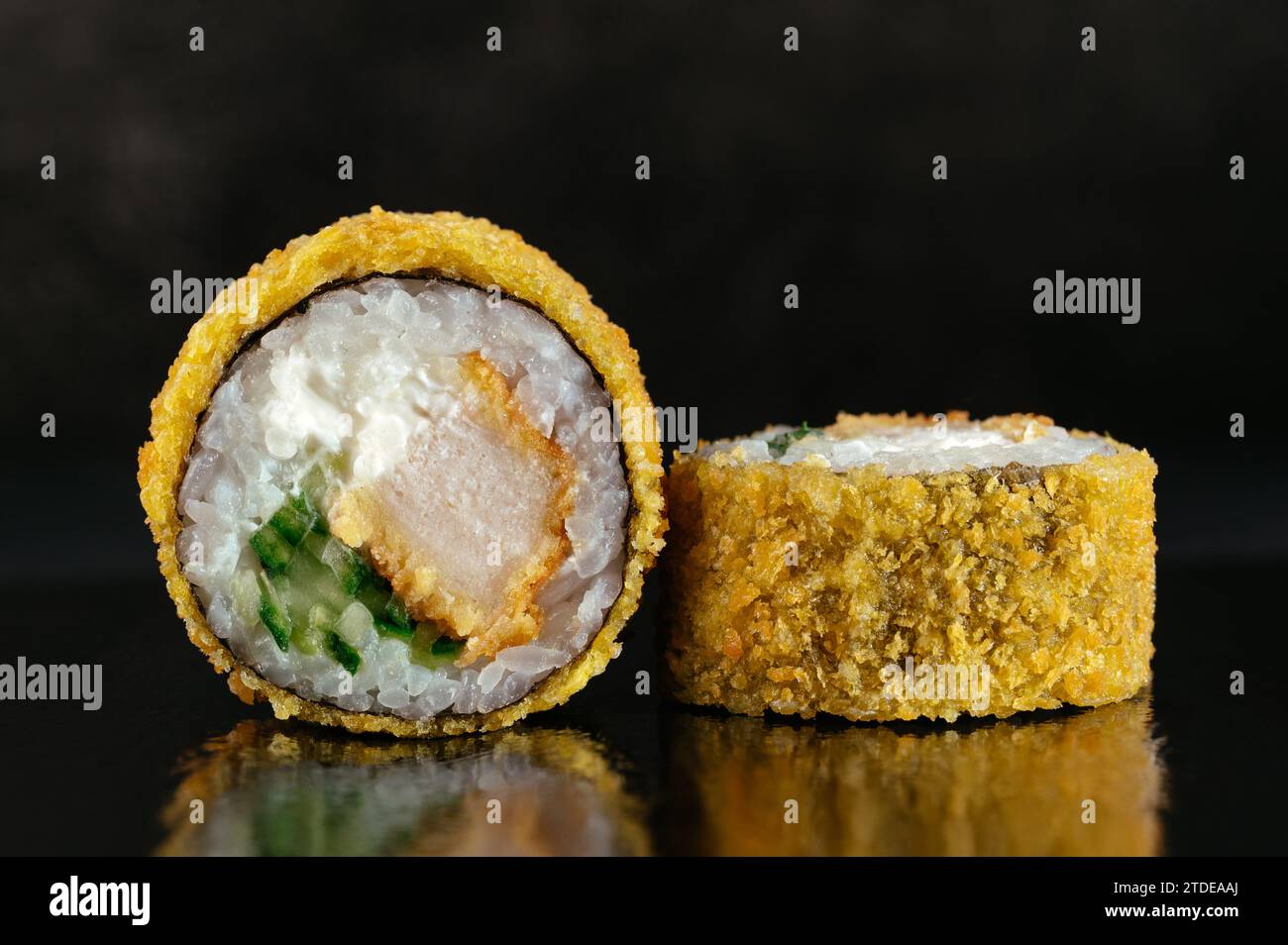 Deep-fried Japanese sushi rolls on a dark background with reflec Stock ...