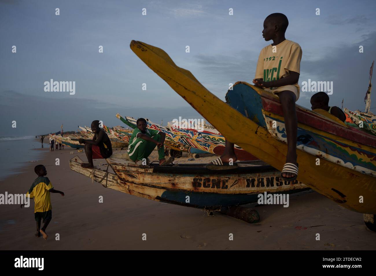 Boys sit atop pirogues, Senegalese boats used by fishermen and migrants ...