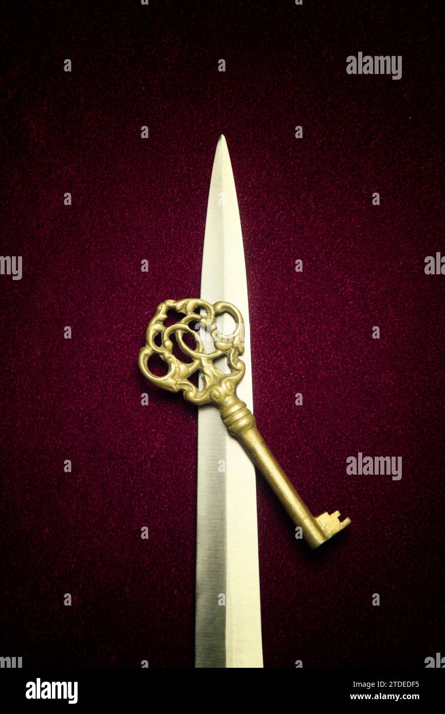 Old key over dagger blade Stock Photo - Alamy