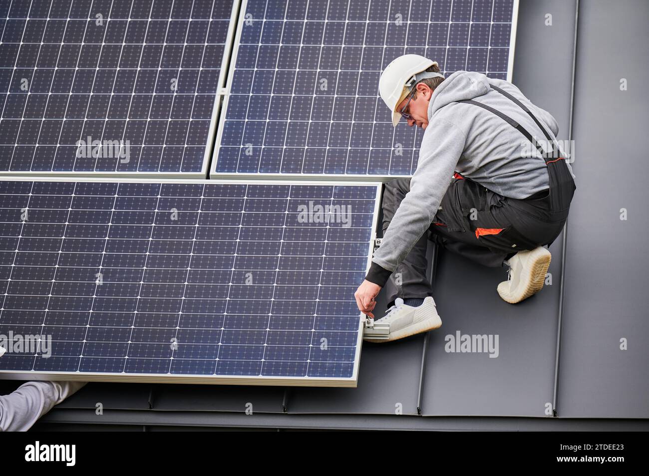 Man installer mounting photovoltaic solar panels on roof of house ...