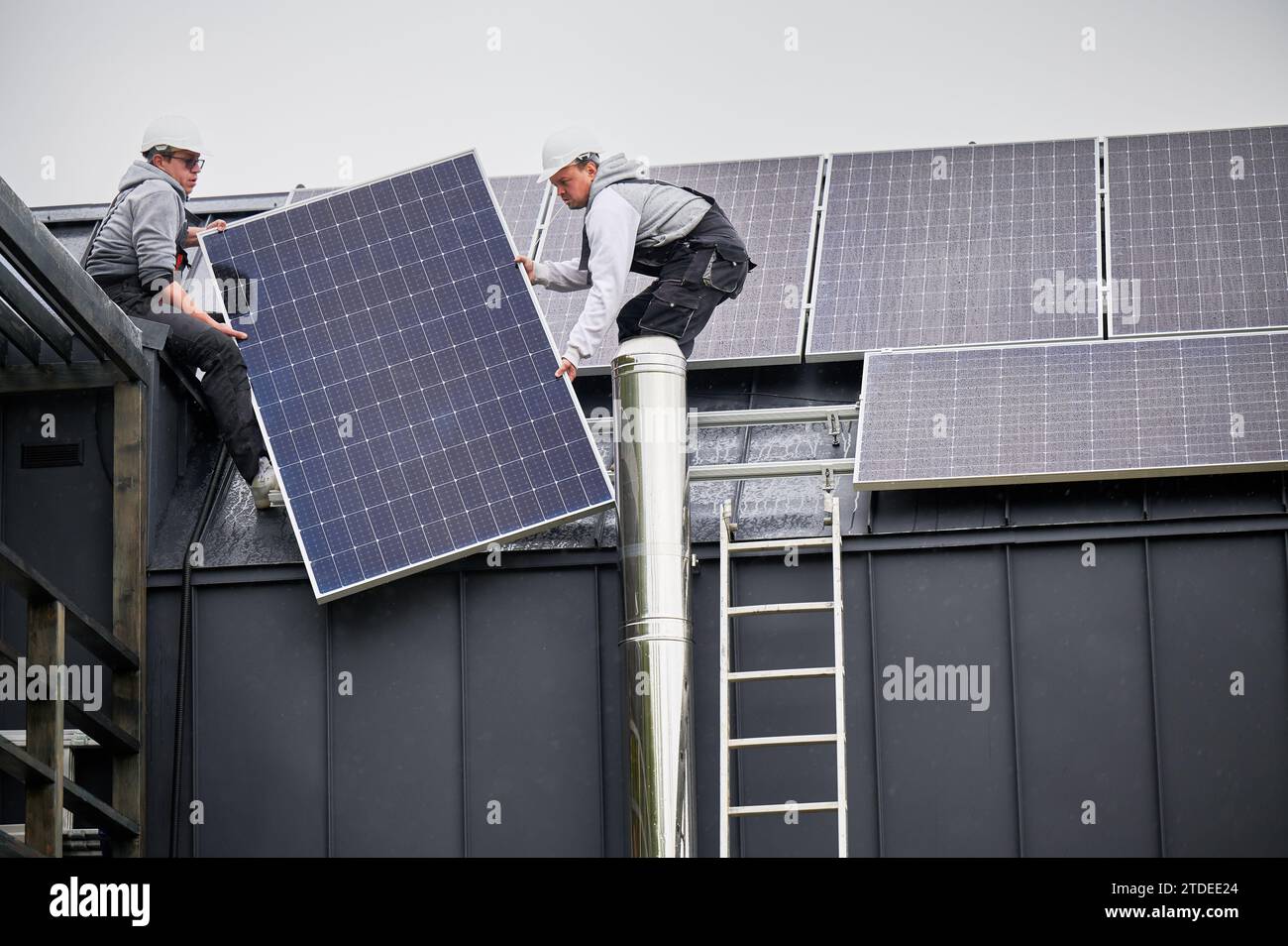 Men builders installing solar panel system on roof of house ...
