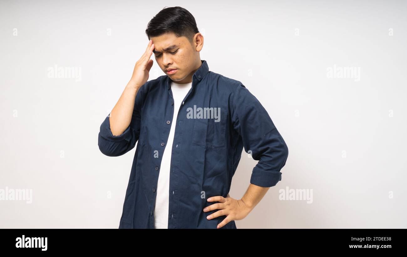 Asian young man showing in pain expression while touching his head ...