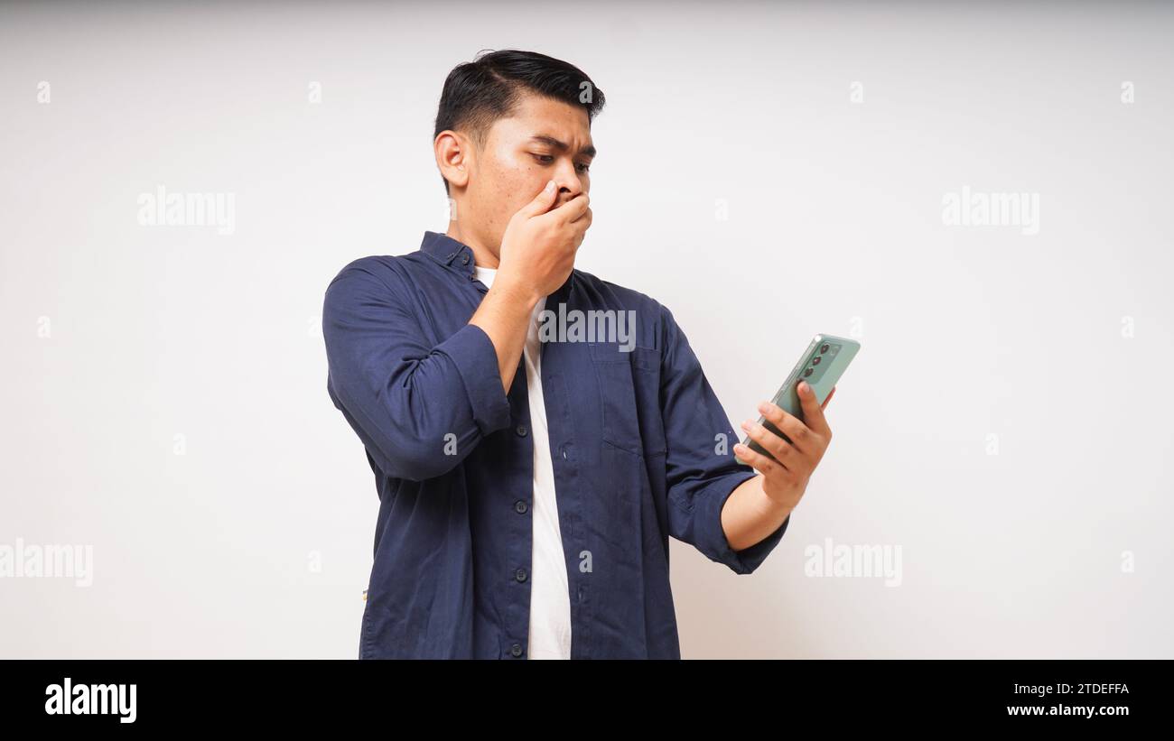 Young Asian man showing shocked face expression while using mobile ...